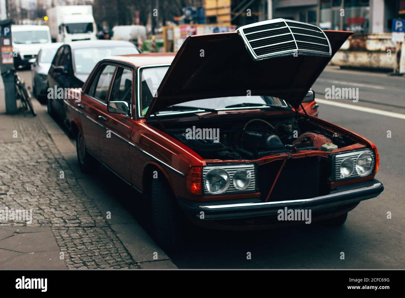 Old fashioned red vintage car with opened hood parked on street of town ...