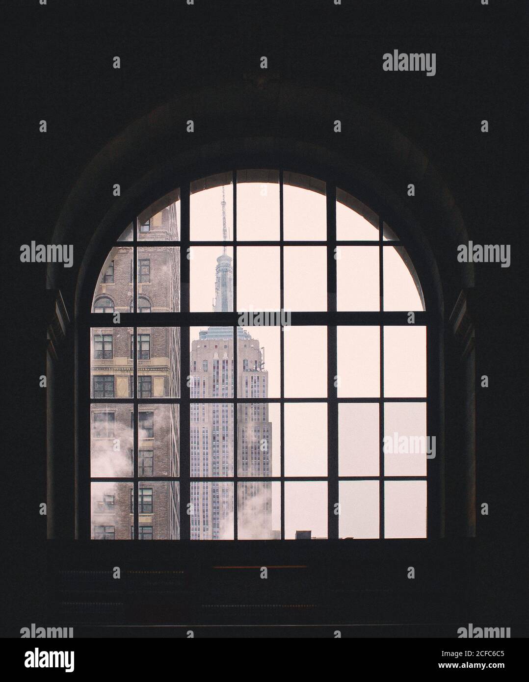 Trough arched window view on famous Empire State building in smoke on ...
