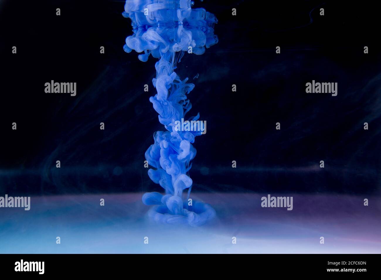 blue color paint pouring in water on dark background Stock Photo - Alamy