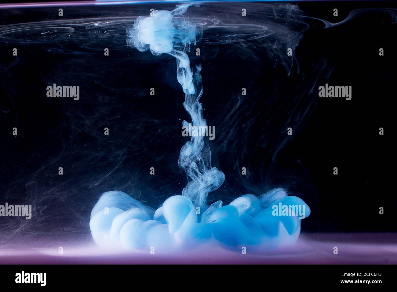 blue color paint pouring in water on dark background Stock Photo - Alamy