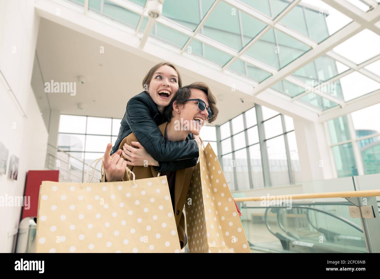 Happy beautiful young couple holding shopping bags while standing in ...