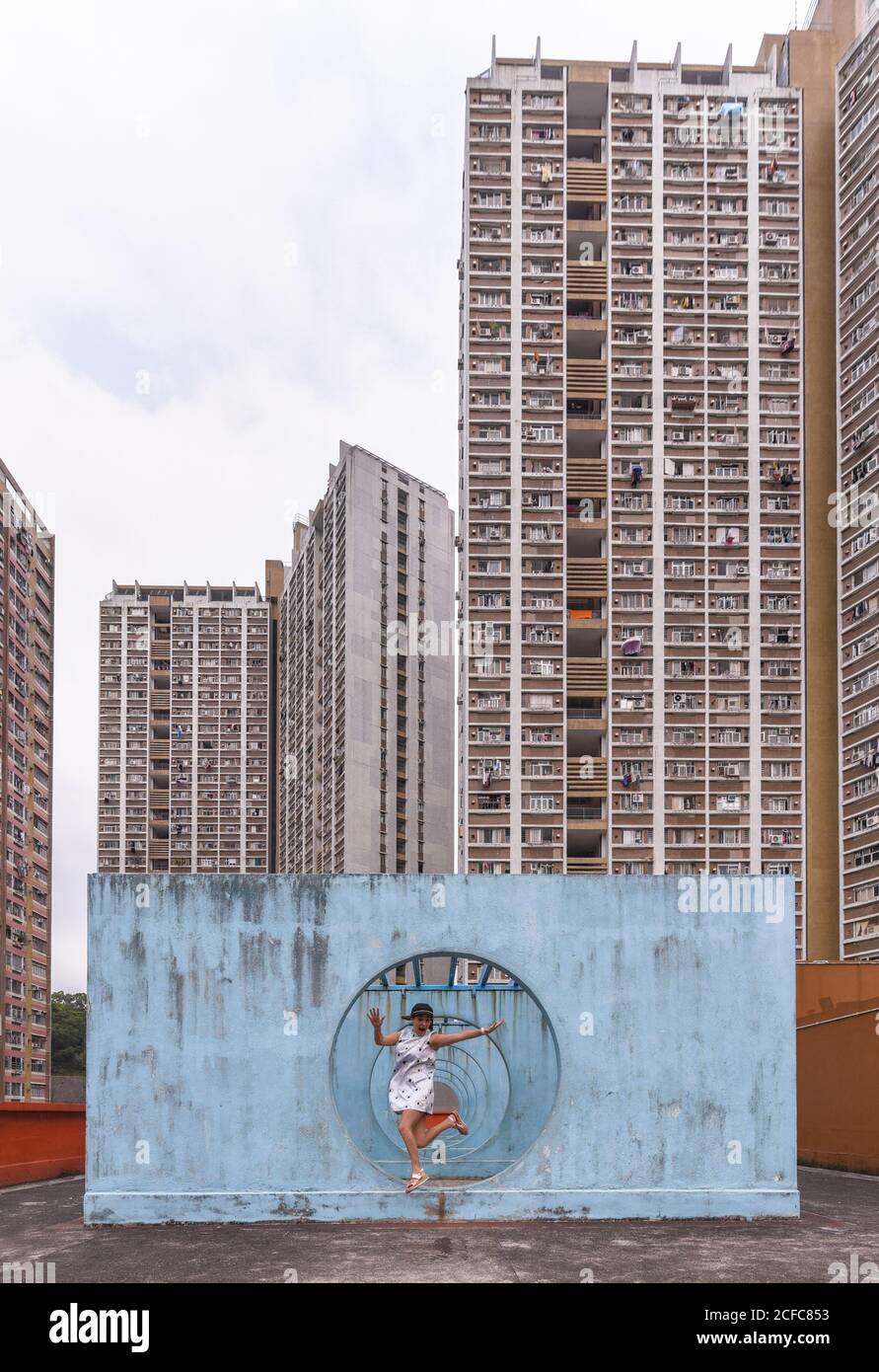 Female in summer dress jumping on concrete base of unusual city ...