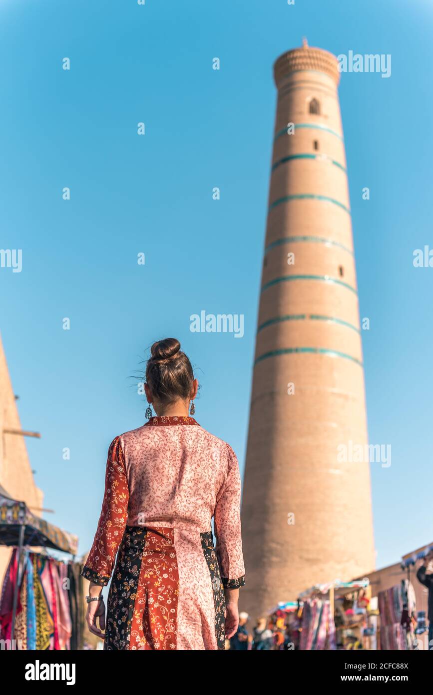 Back view of female in colorful dress walking along open air oriental ...