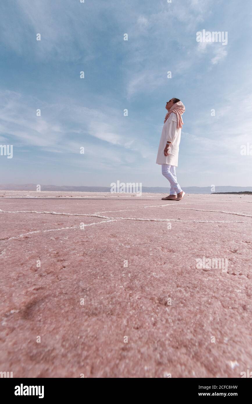 From below side view of calm pensive unrecognizable female in white ...