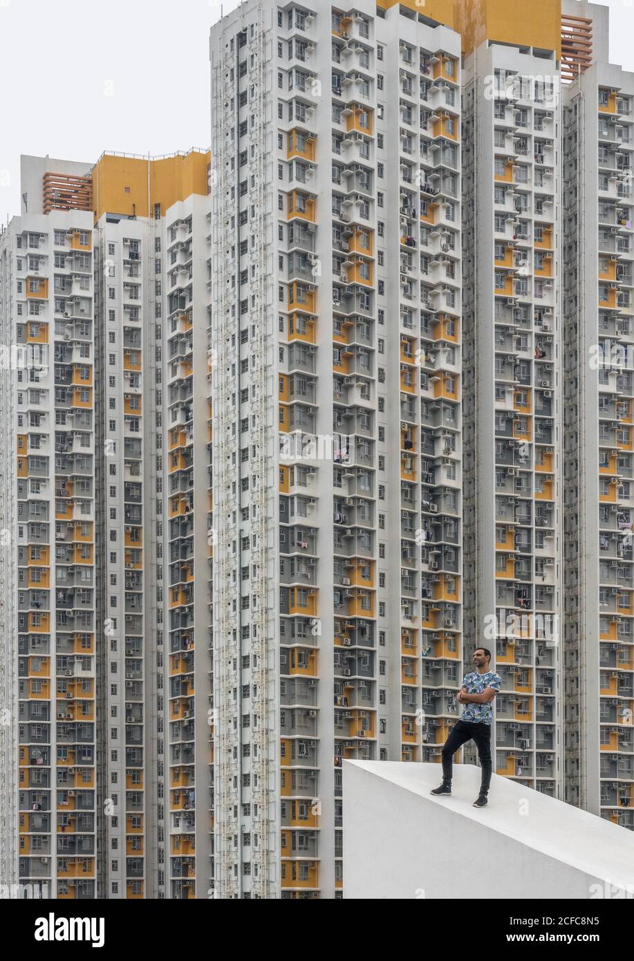 Relaxed male in casual clothes posing on concrete sloping roof against ...
