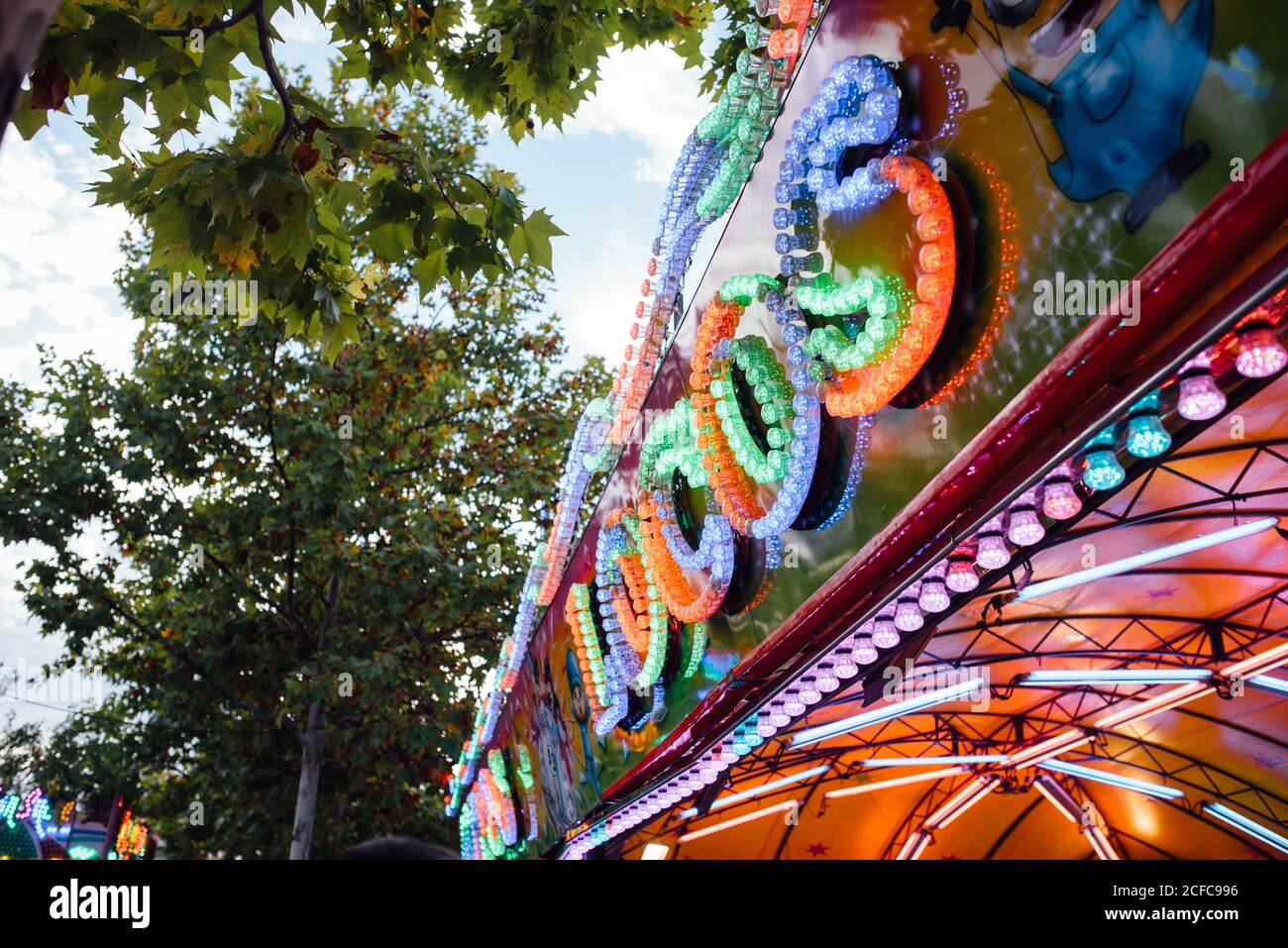 From below colorful glowing sign of modern carousel amidst tree ...