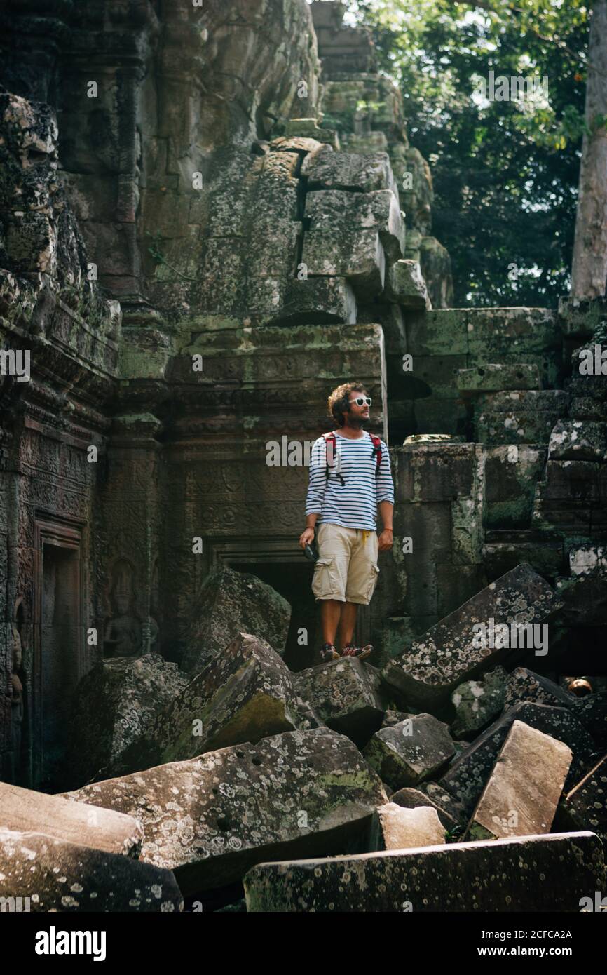 Traveling man with backpack standing on pile of mossy stone blocks ...
