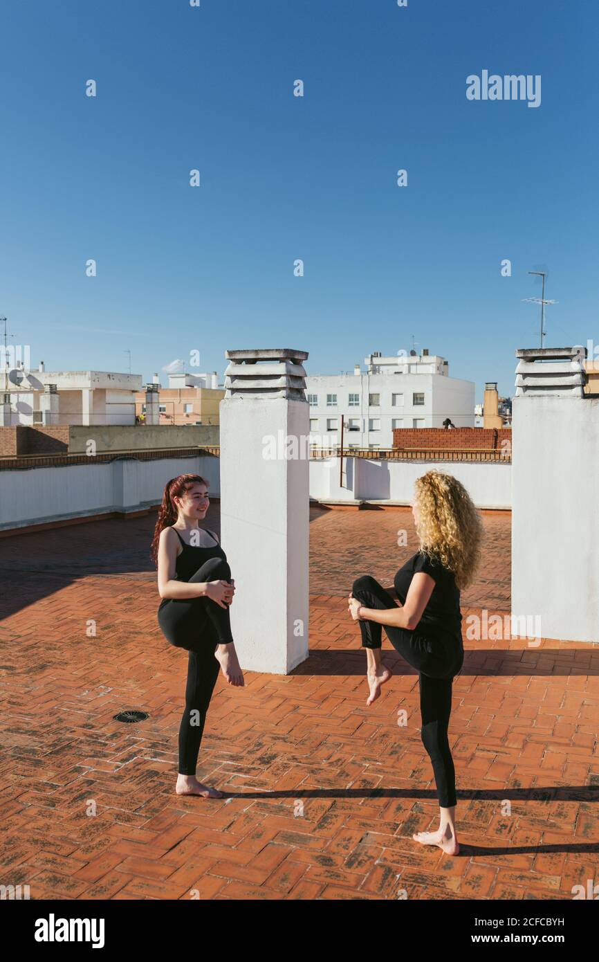 Women practicing balance yoga pose on rooftop Stock Photo - Alamy