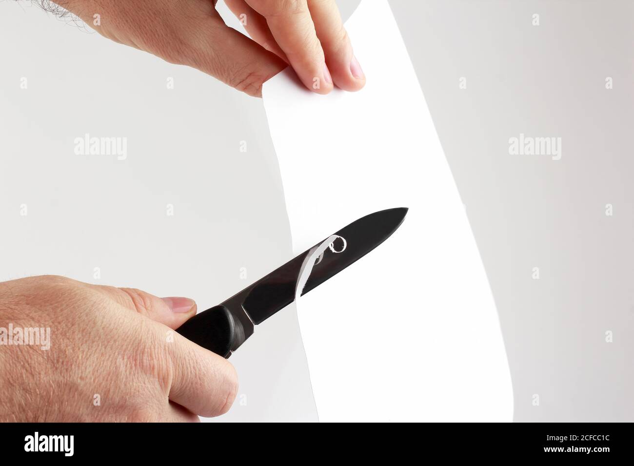 the blade of a sharp knife cut across the white paper Stock Photo - Alamy