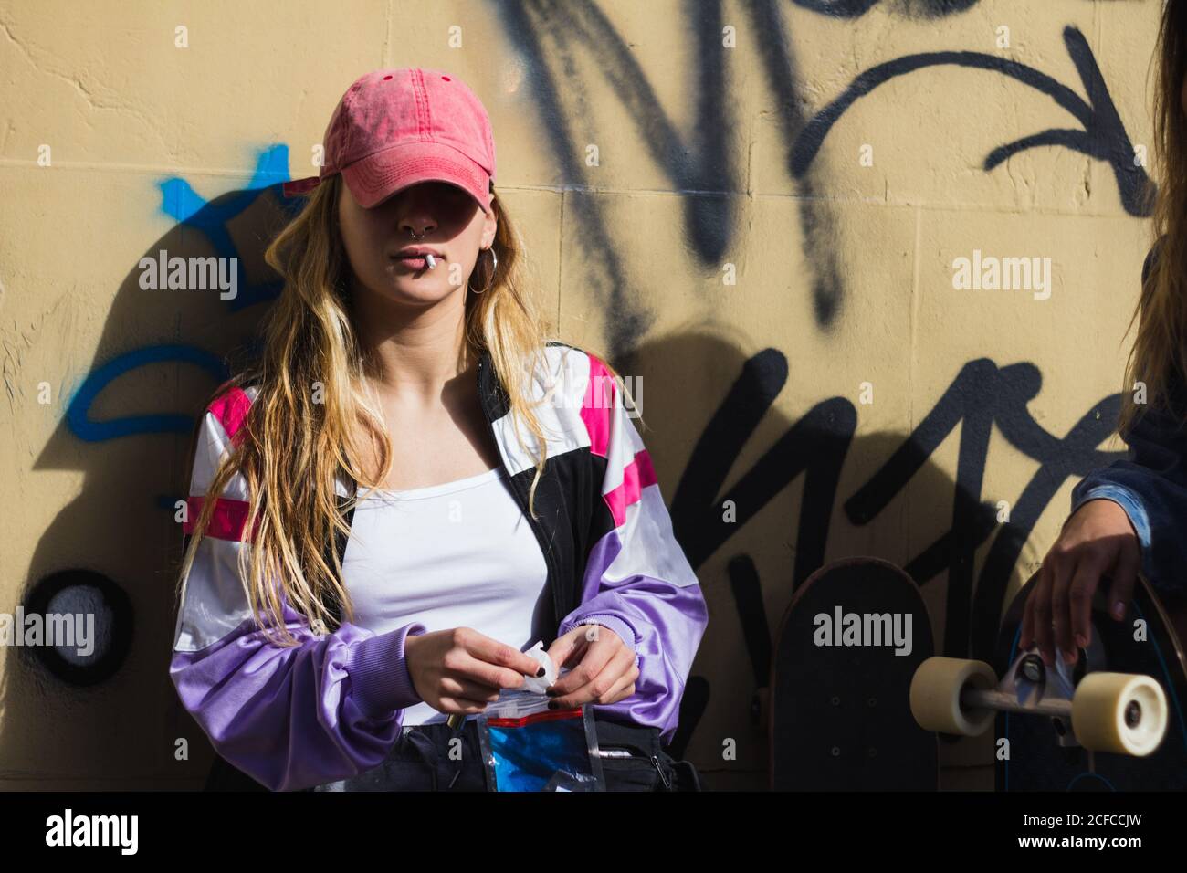 Rebellious female millennial standing near girlfriend with skateboard ...