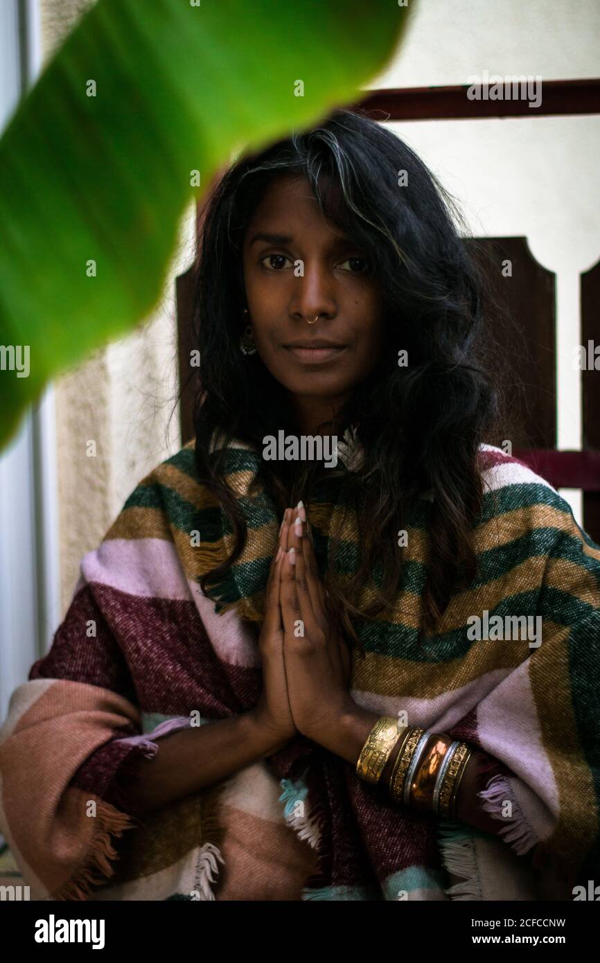 Young ethnic spiritual female in traditional clothes keeping hands in ...