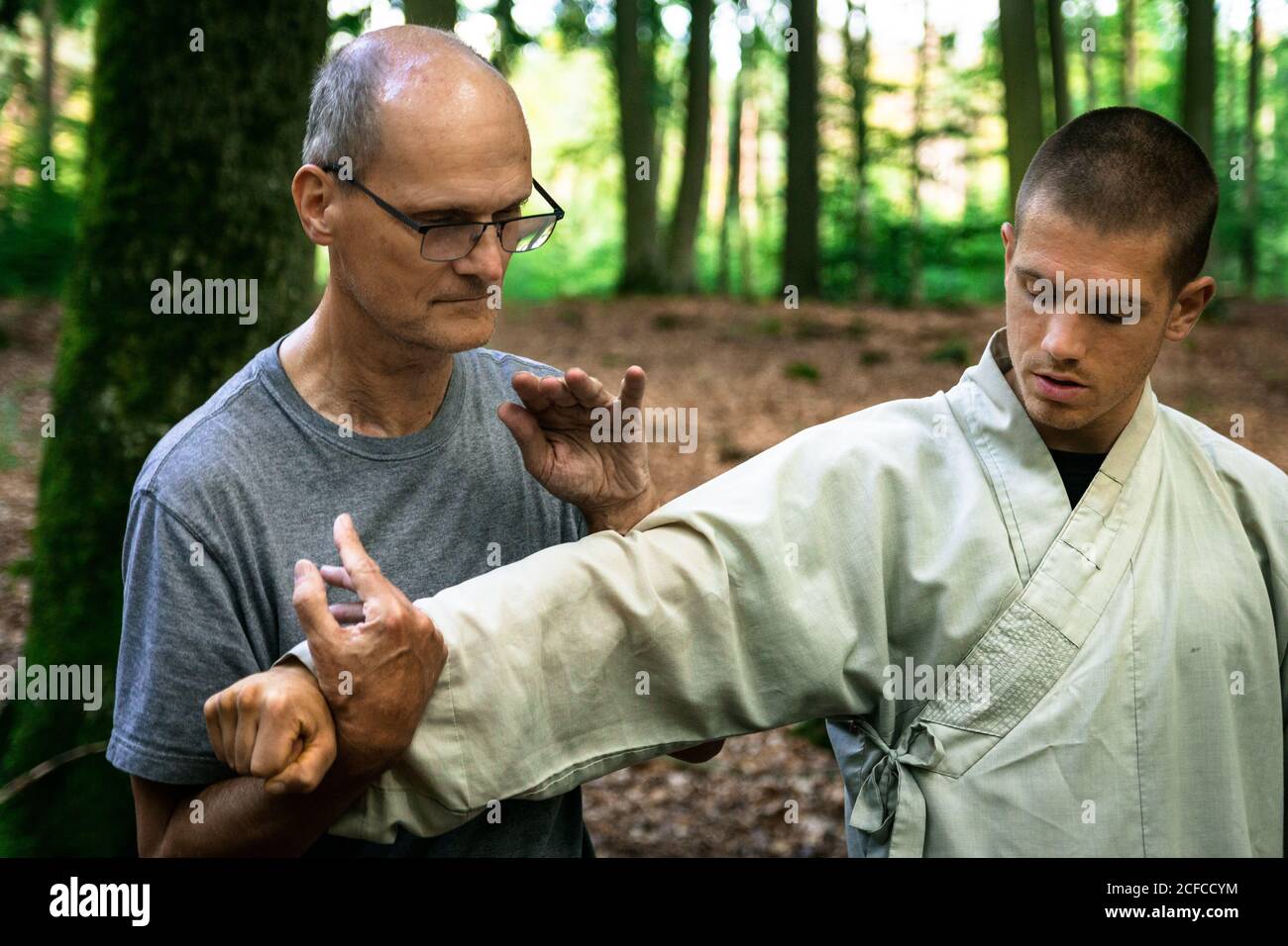 Bald mature instructor showing exercise to young man in uniform while ...