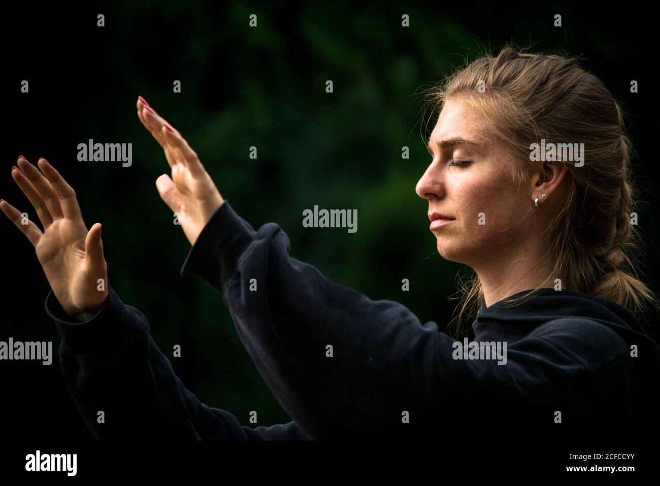 Concentrated female stretching out arm while doing exercise during ...