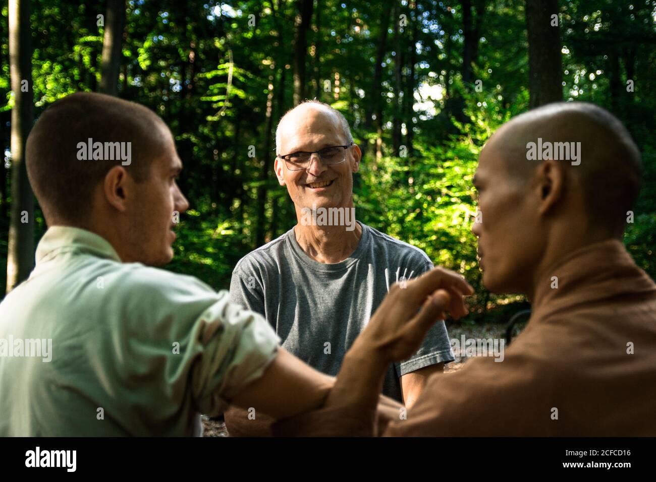 Bald mature instructor showing exercise to young man in uniform while ...