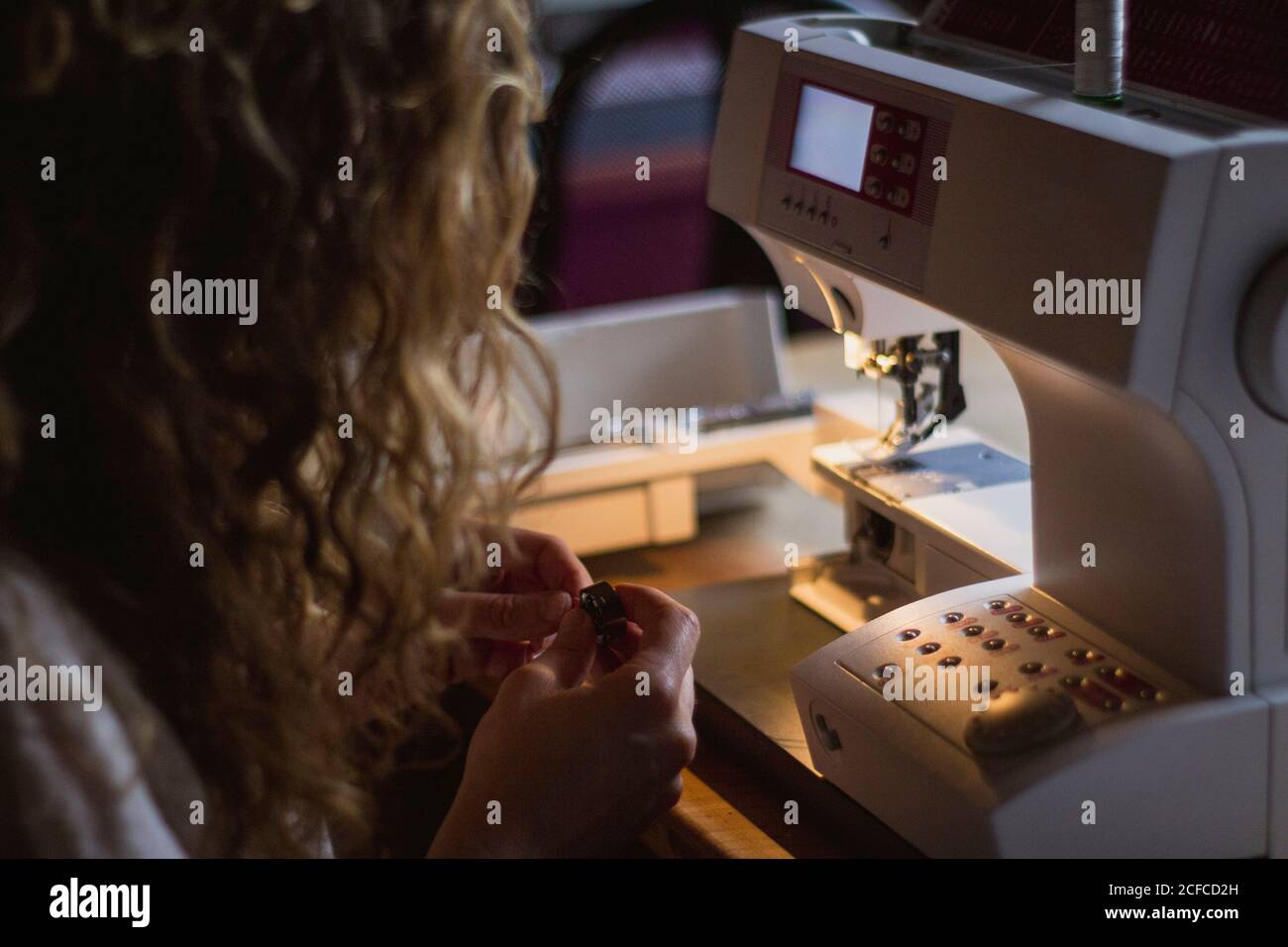 Back view of anonymous crop Woman using sewing machine making clothes ...
