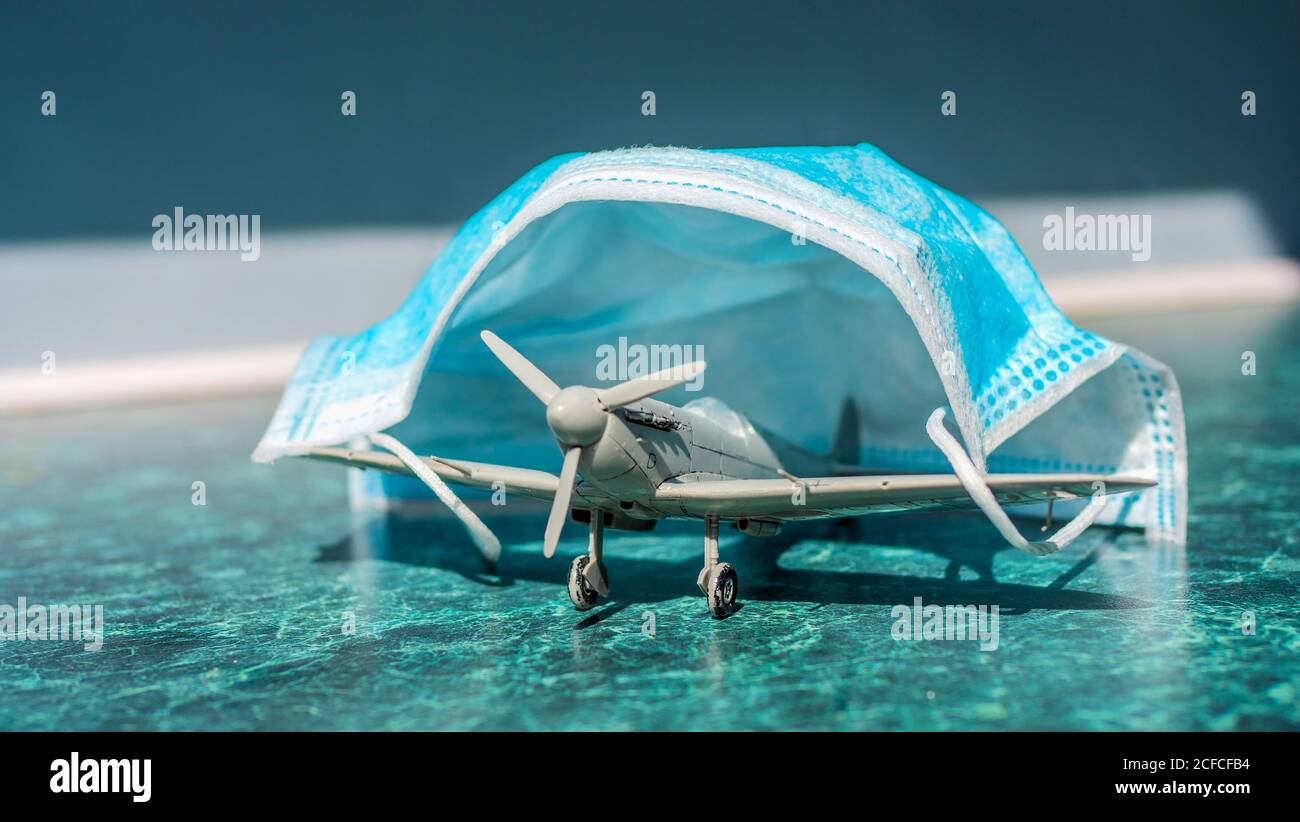 A face mask placed like a parachute on a small toy plastic airplane ...