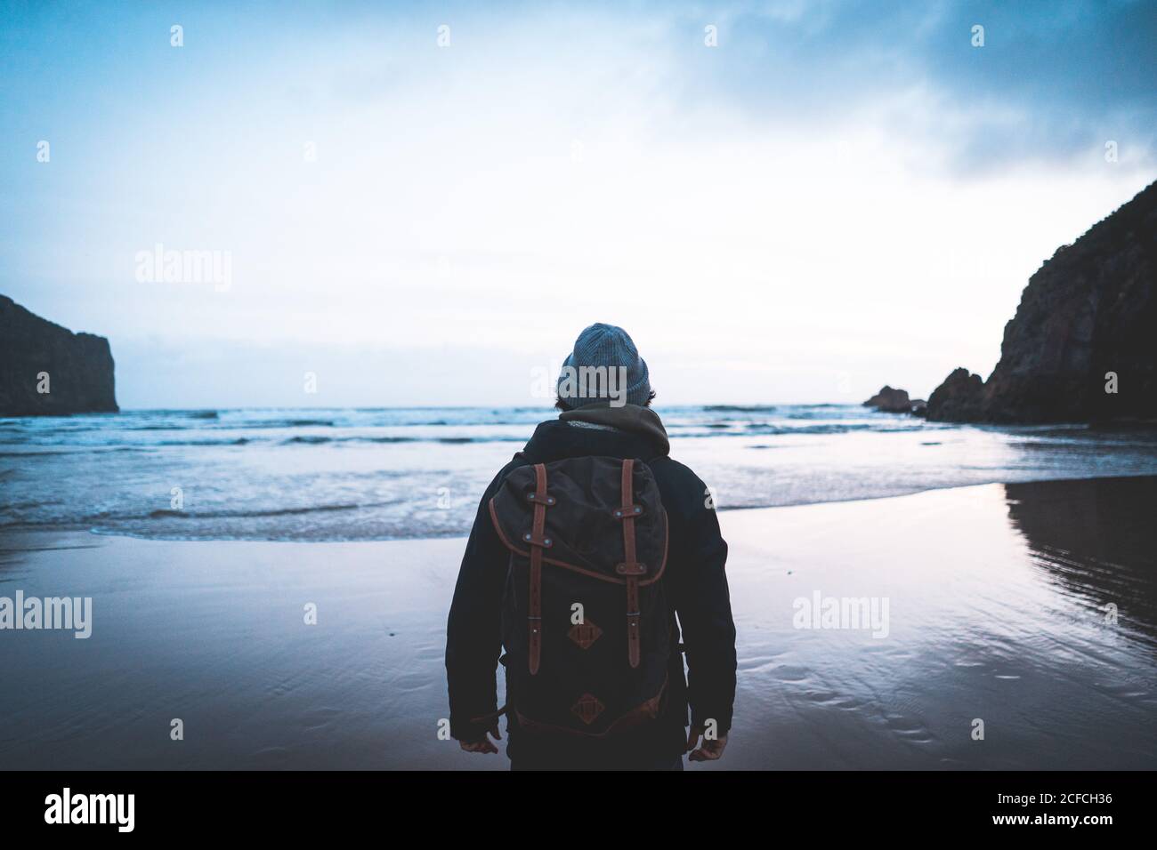 Back view of anonymous traveler in jacket with backpack contemplating ...