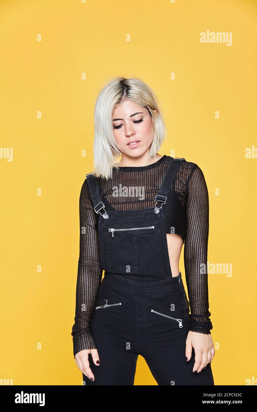 Attractive blonde Woman in black overalls standing and looking down on ...