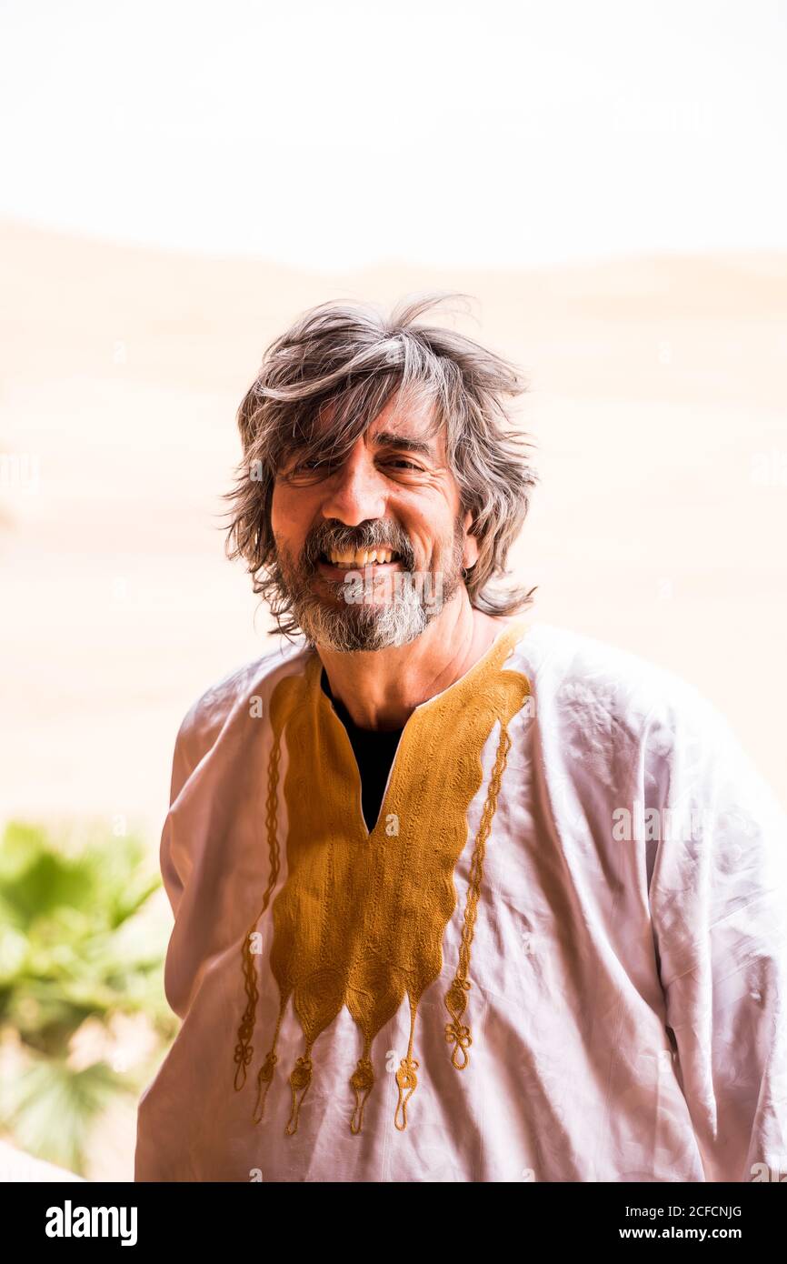 Portrait of adult man in long outfit with desert in the background and ...