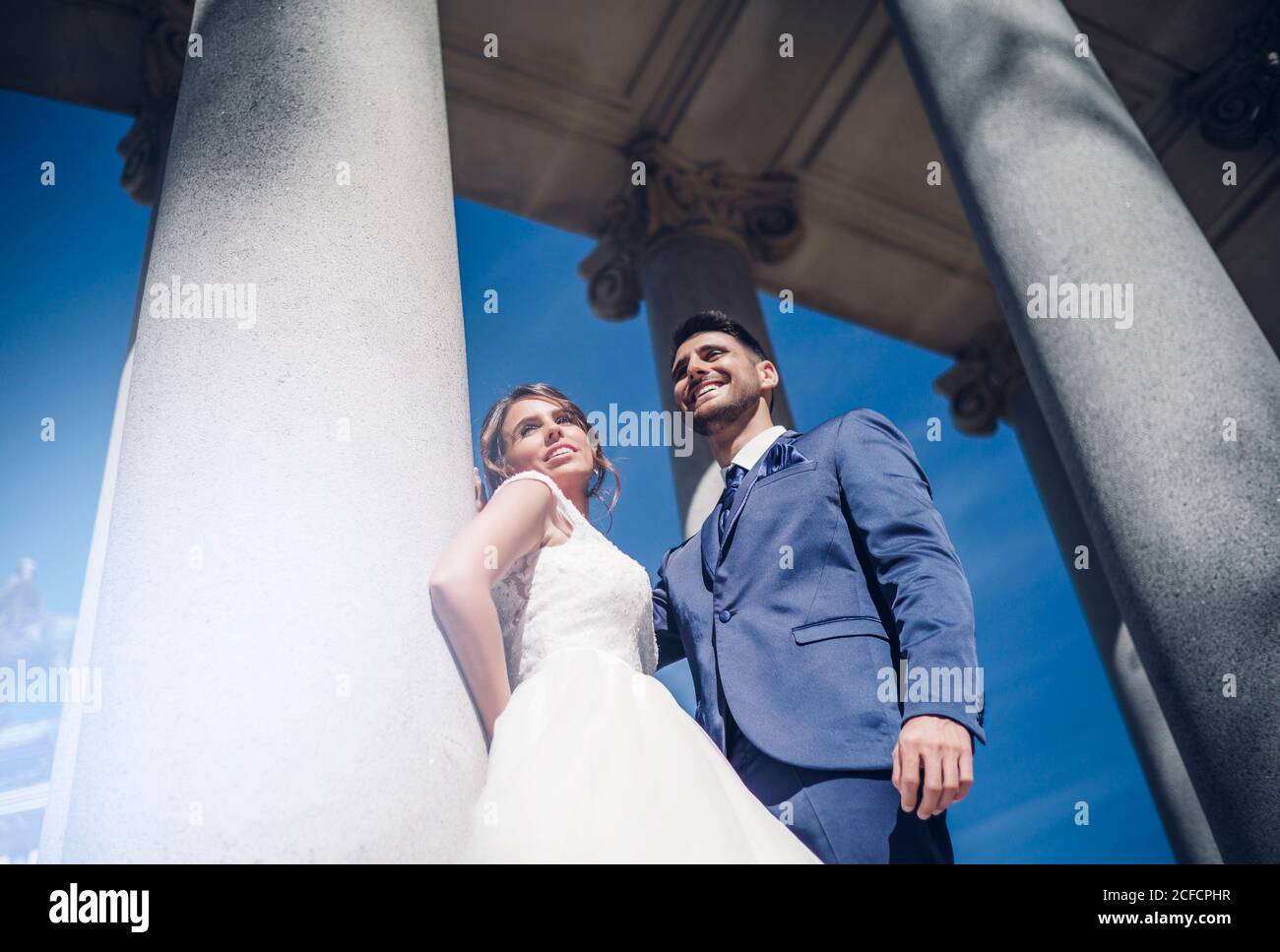 From below side view of young elegant couple in wedding dresses near ...