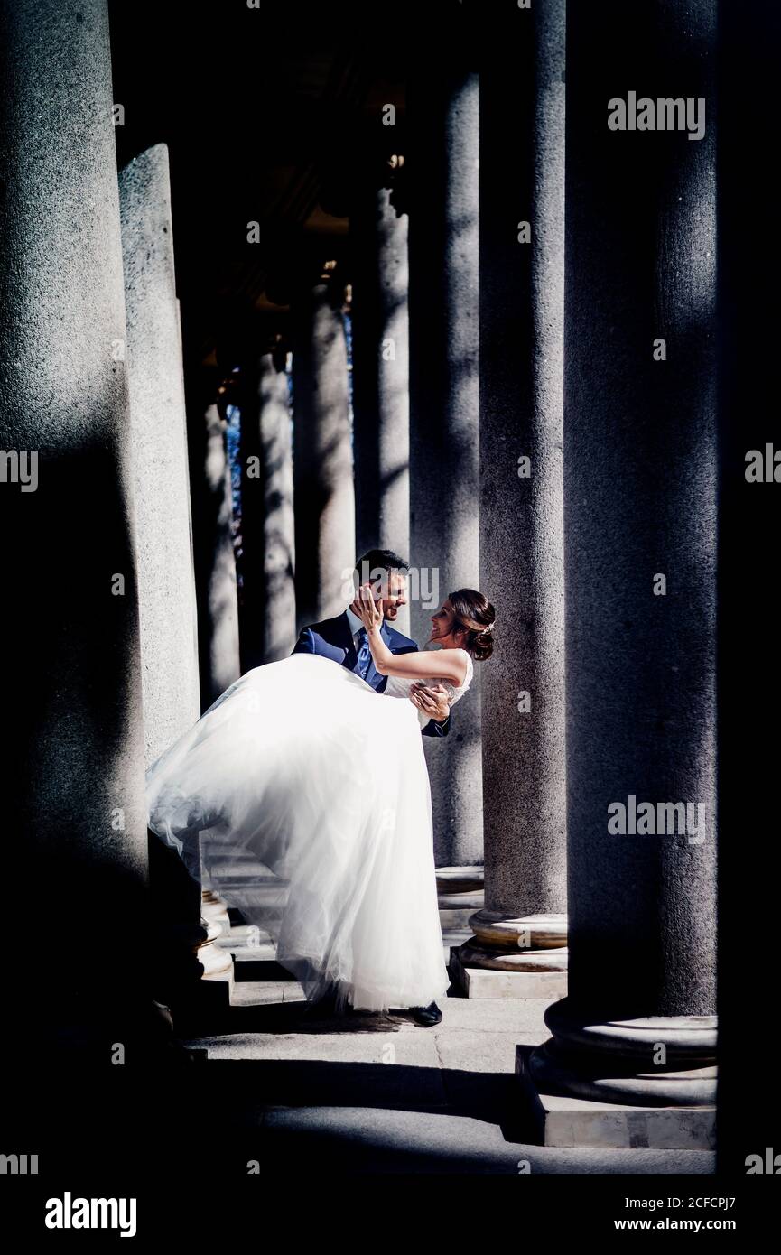 Side view of young elegant man holding on hands Woman in wedding dress ...