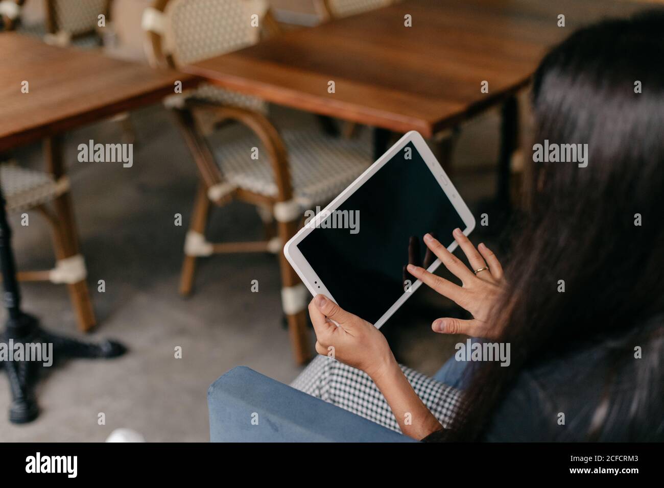 From above side view of crop young female using tablet with empty black ...
