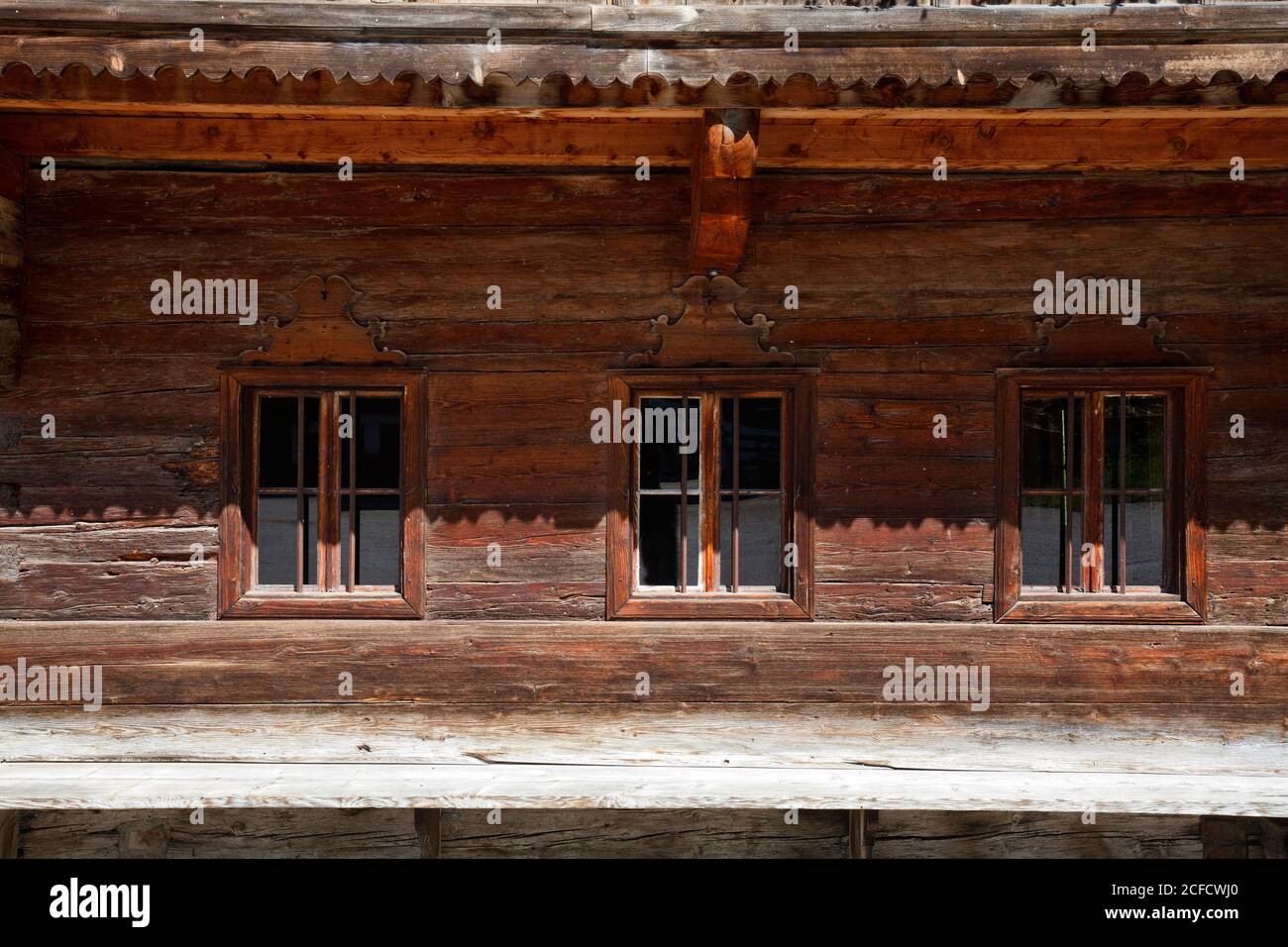 three small windows in the wooden beam wall of a mountain farm on ...