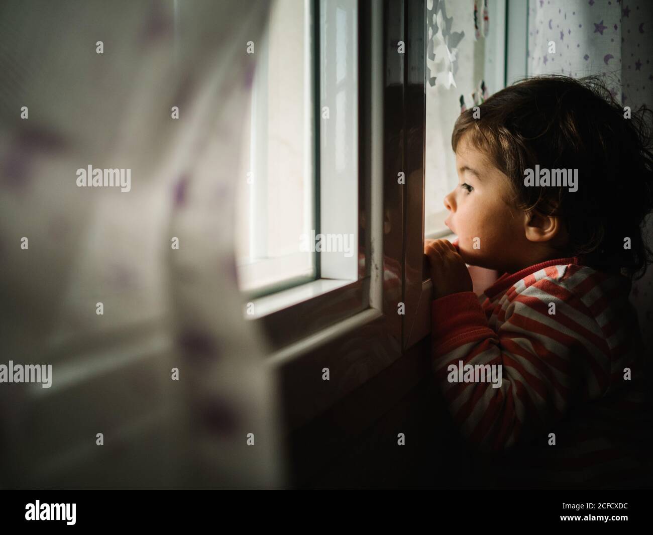 small girl peering through window at home Stock Photo - Alamy