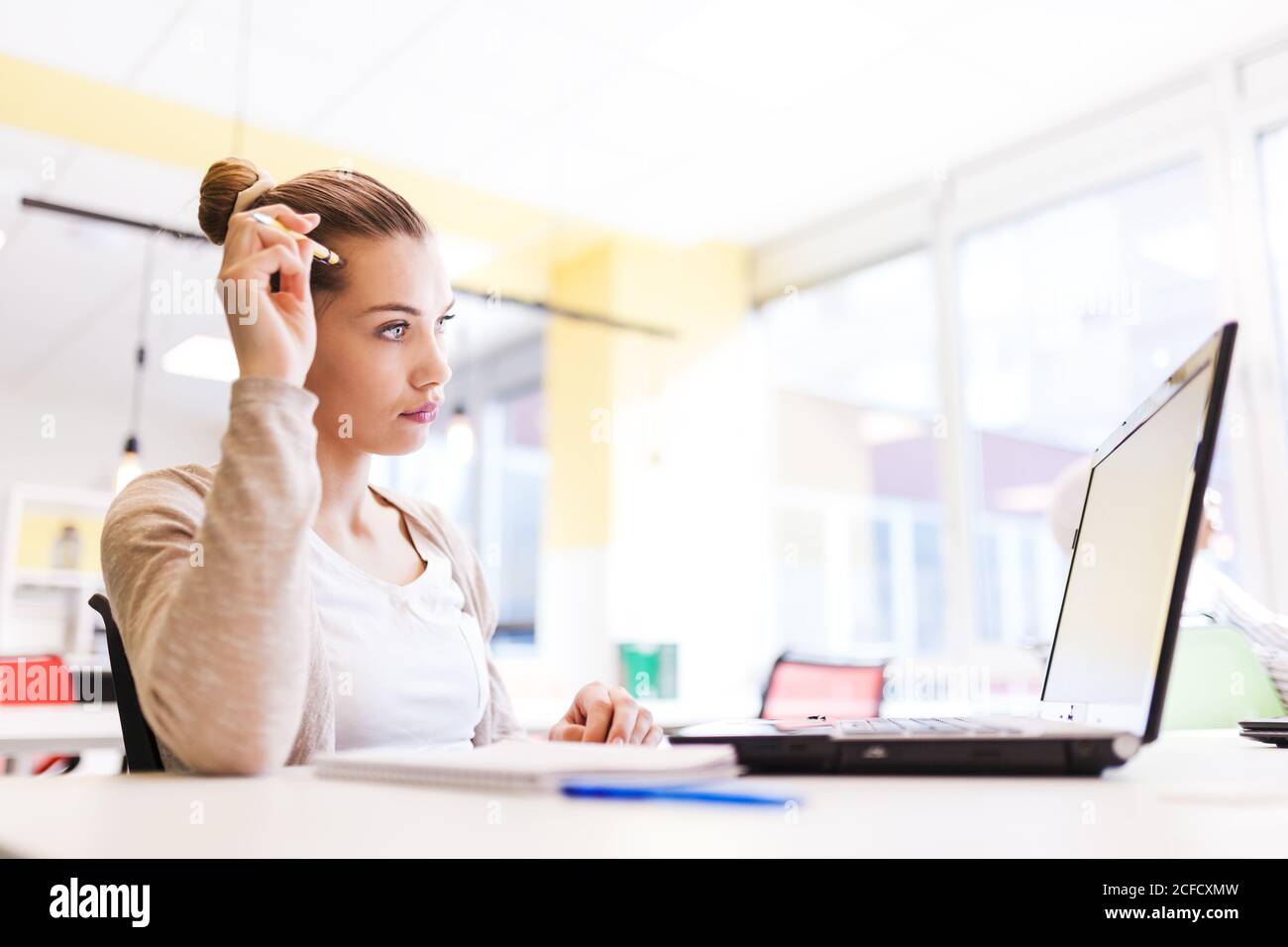 Beautiful girl working on a laptop in a modern coworking space ...