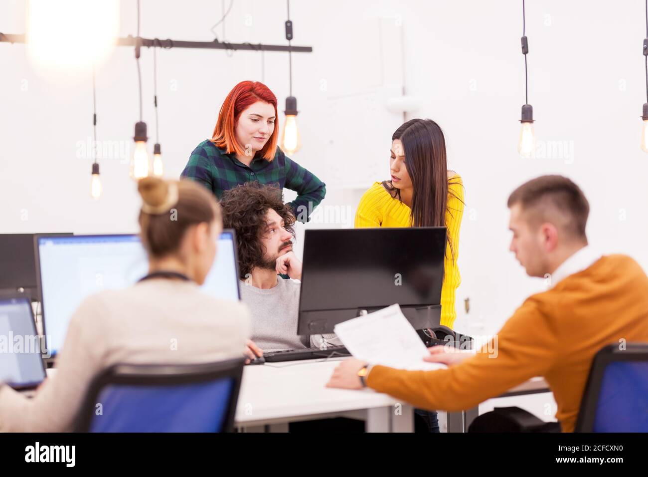 Creative young individuals working on desktop computers in a modern ...