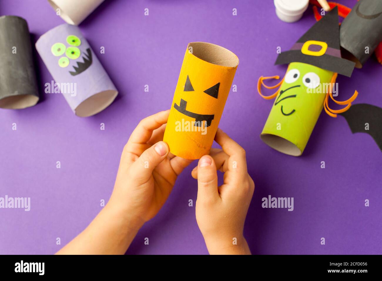 Kid hands holds a Halloween decorative toy from toilet roll. Boy mades ...