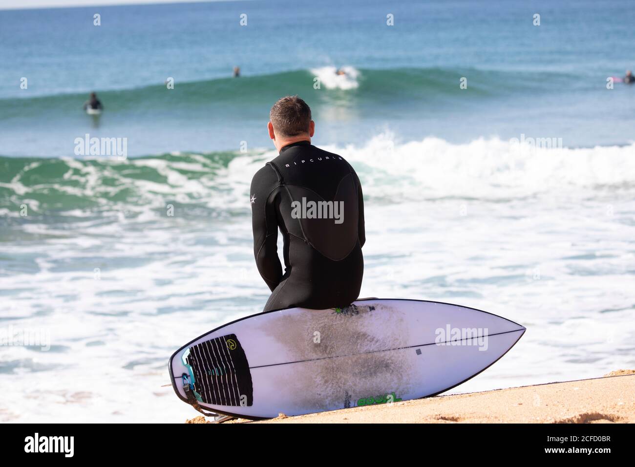 Male surfer rests on his surfboard on Narrabeen beach in Sydney,NSW ...