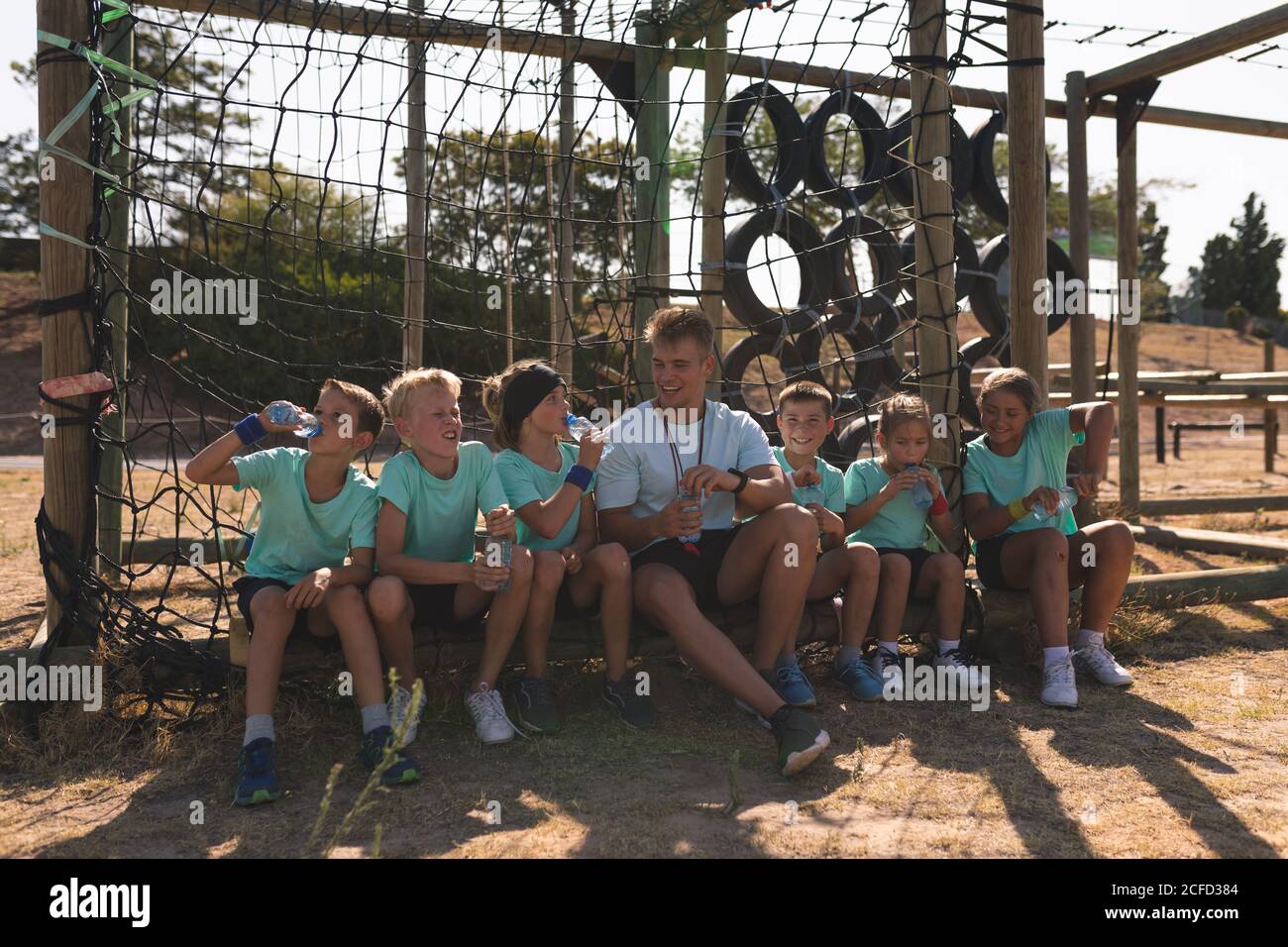 Male fitness coach and kids drinking water at a boot camp Stock Photo ...