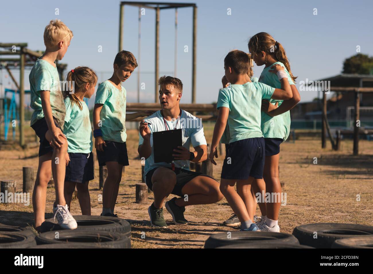 Male fitness coach instructing kids at a boot camp Stock Photo - Alamy