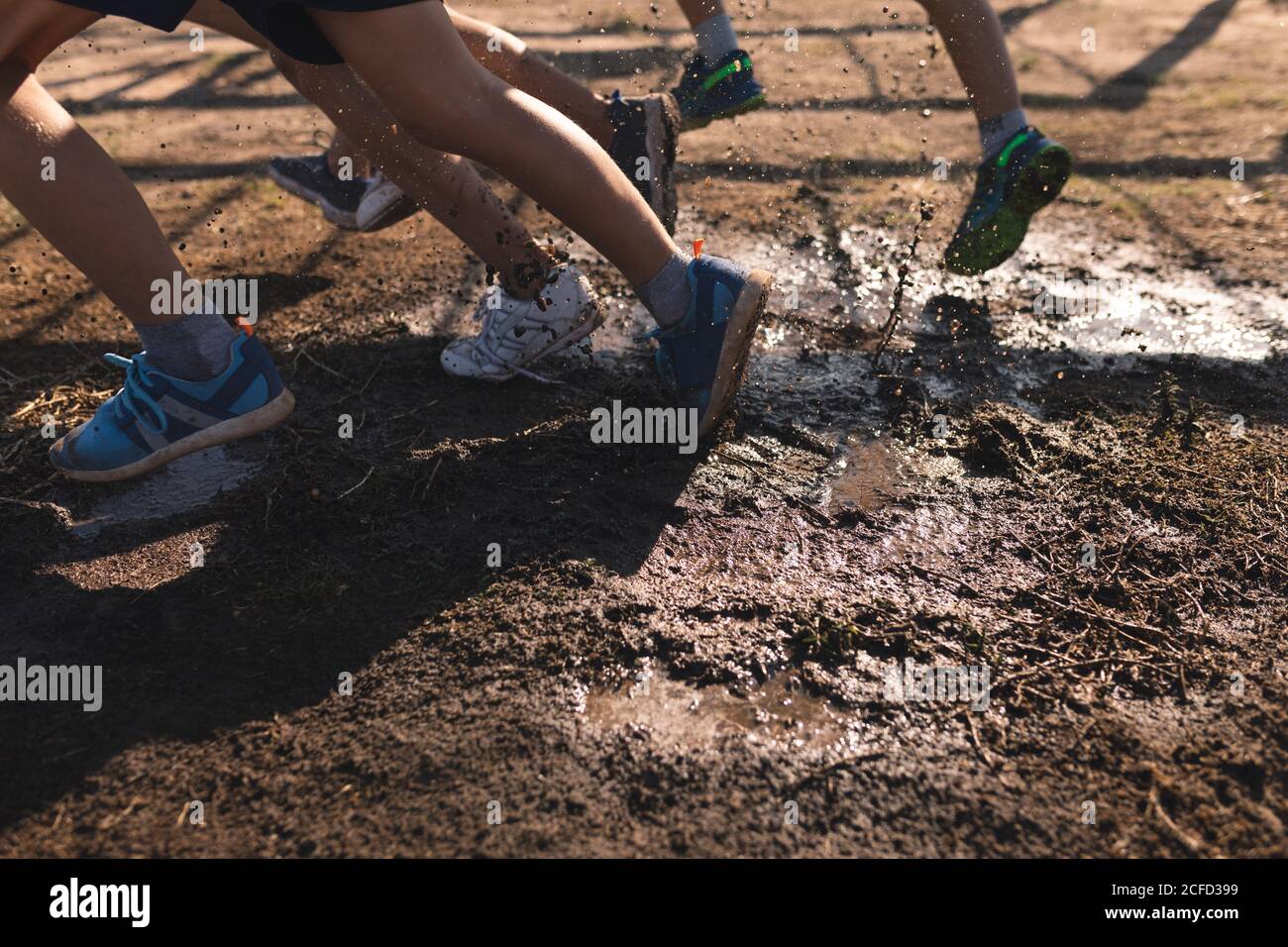 Low section of kids running in mud during obstacle course at a boot ...