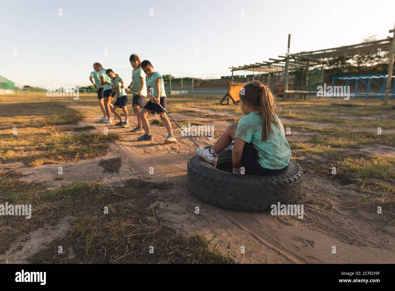 Group of kids pulling a girl sitting on a tire at a boot camp Stock ...