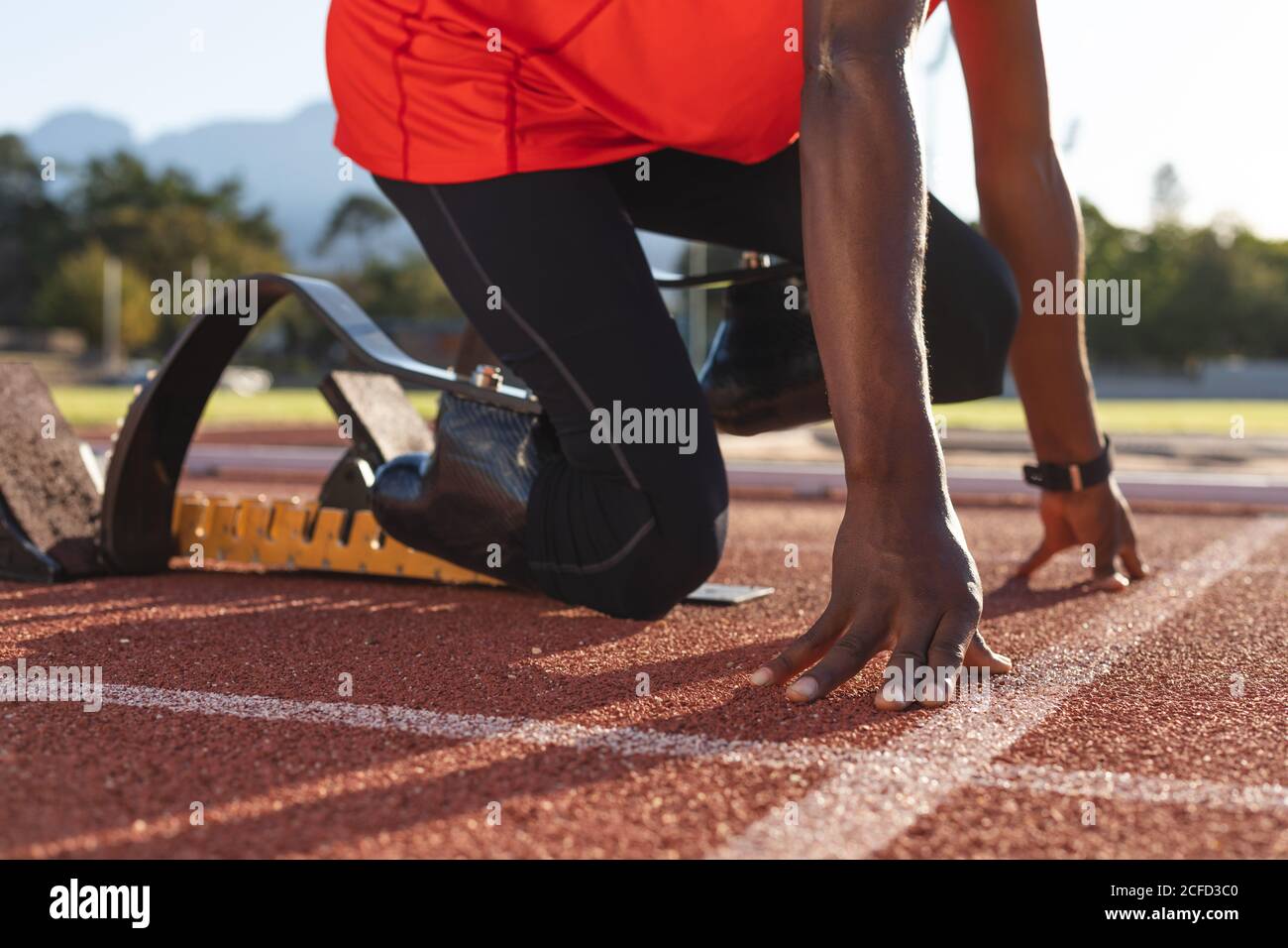 Low section of male athlete with prosthetic legs bending on starting ...