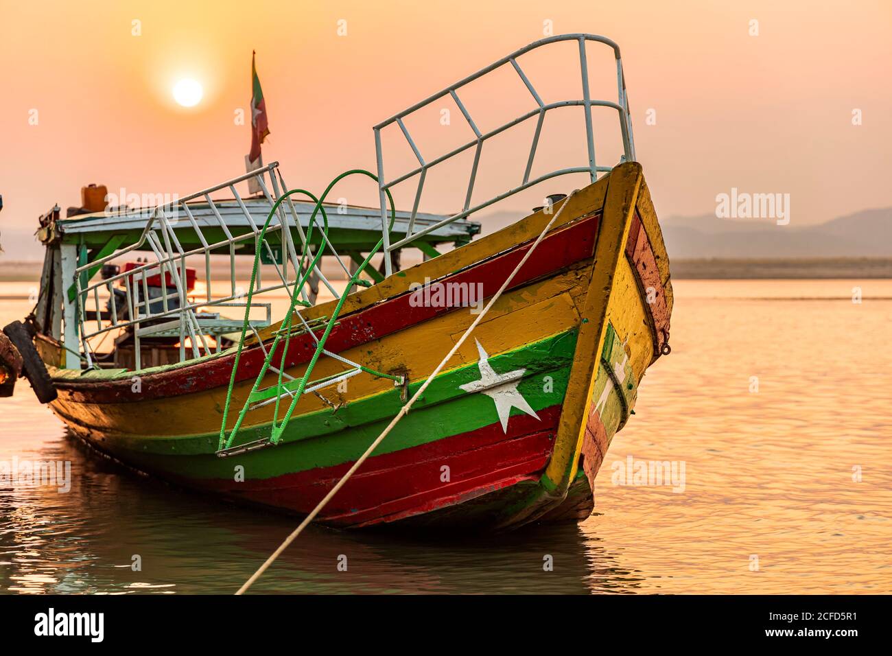 Boat with colors of the flag of Myanmar on the banks of the Irrawaddy ...