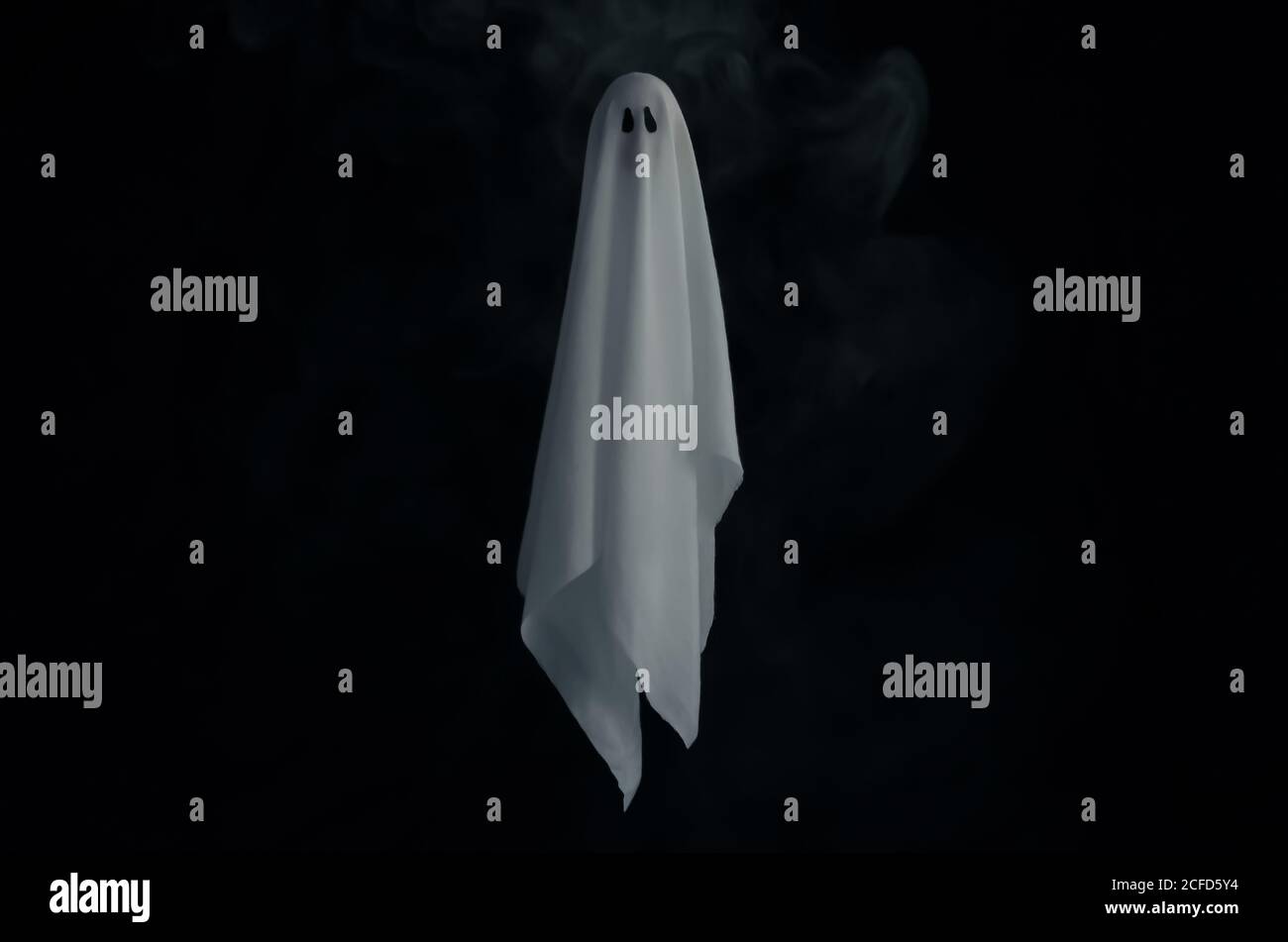 Blurred focus of white ghost sheet in dark background with smoke ...