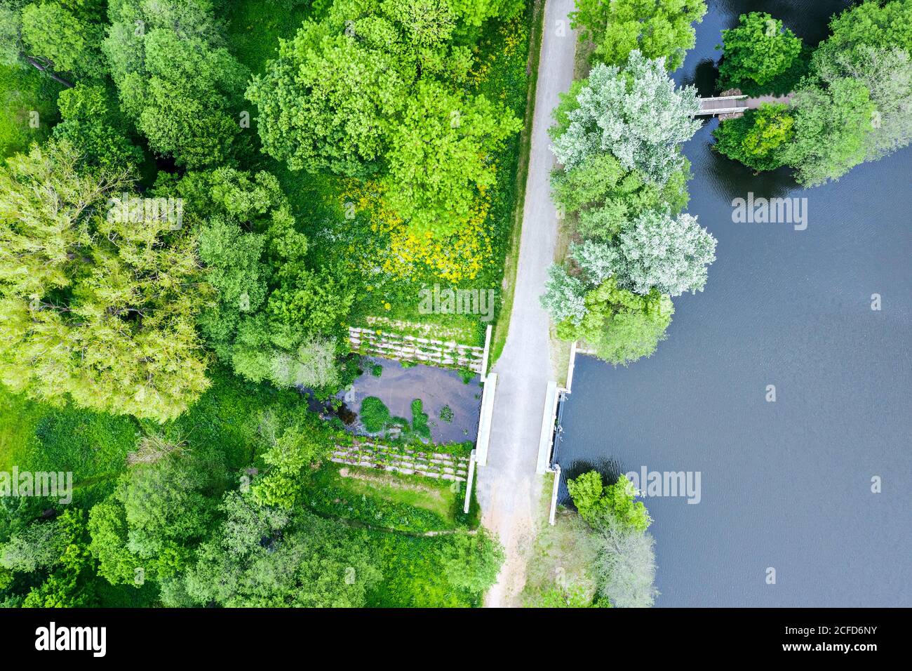 summer park landscape. pond with dam and small island with wooden ...