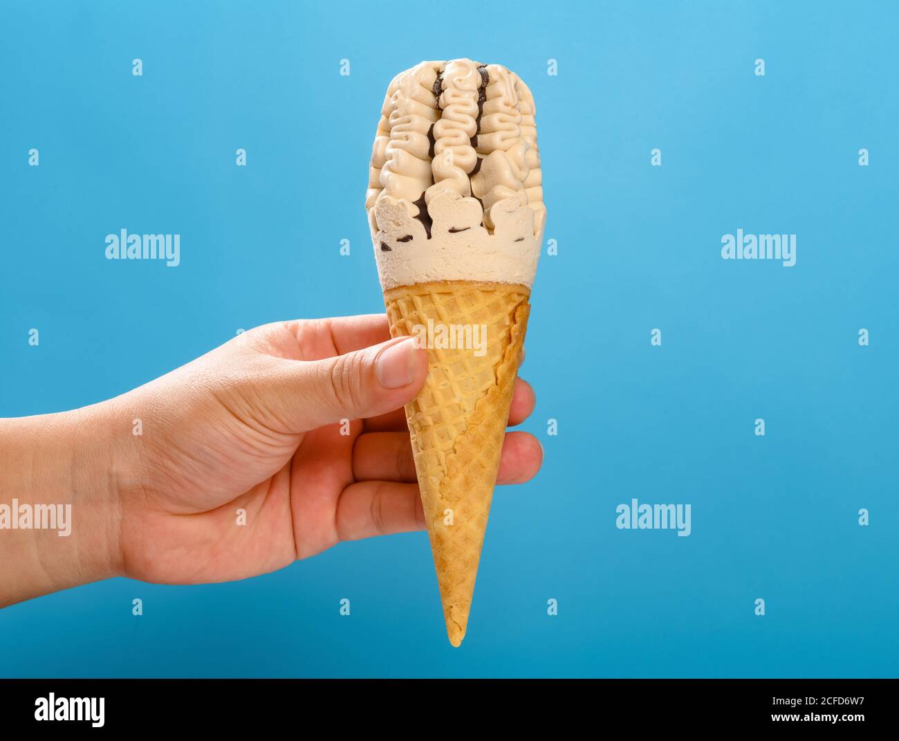 hand holding a fresh milk tea flavor ice cream cone on a blue ...