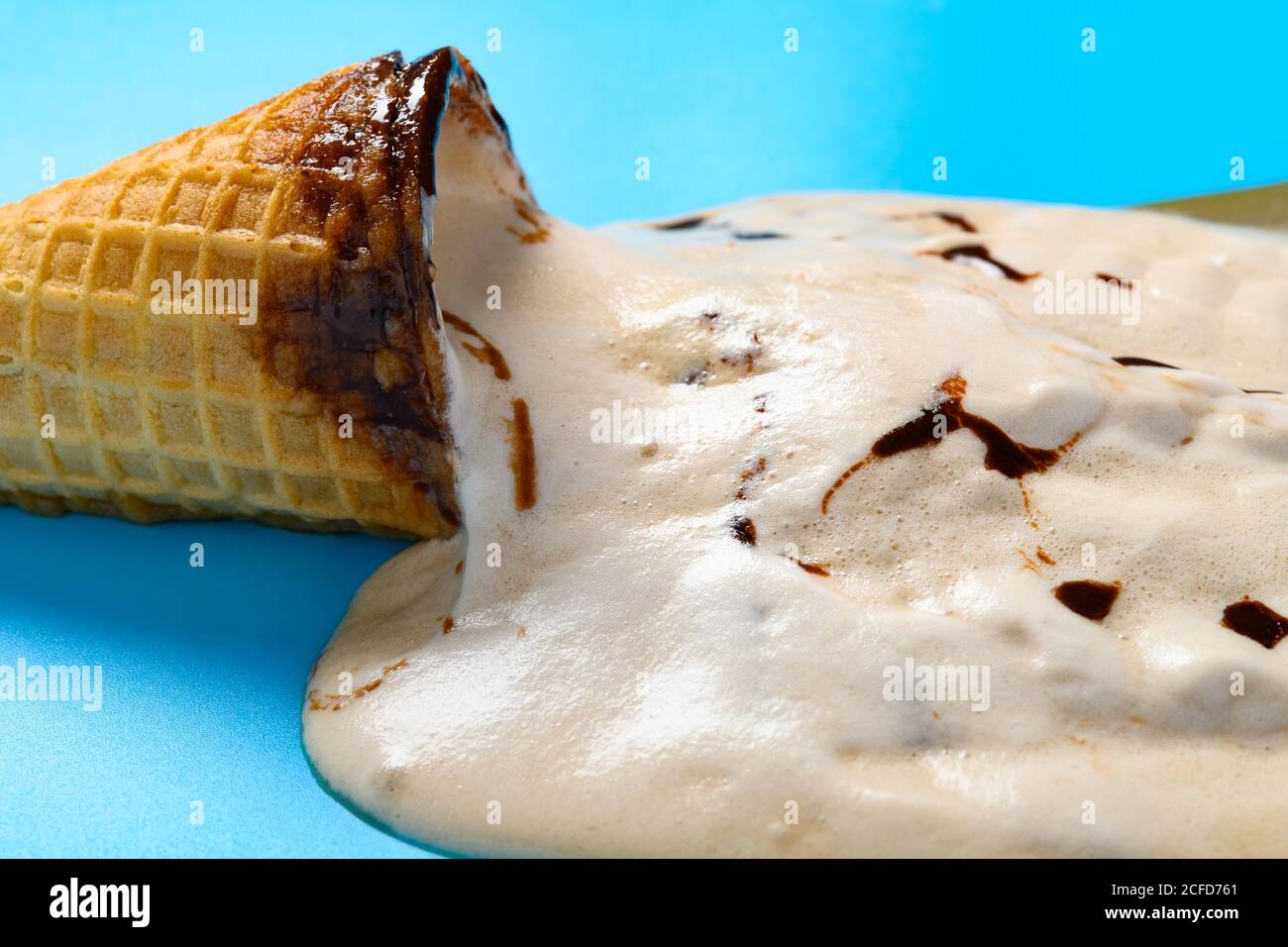 side view milk tea flavor ice cream cone melting on blue background ...