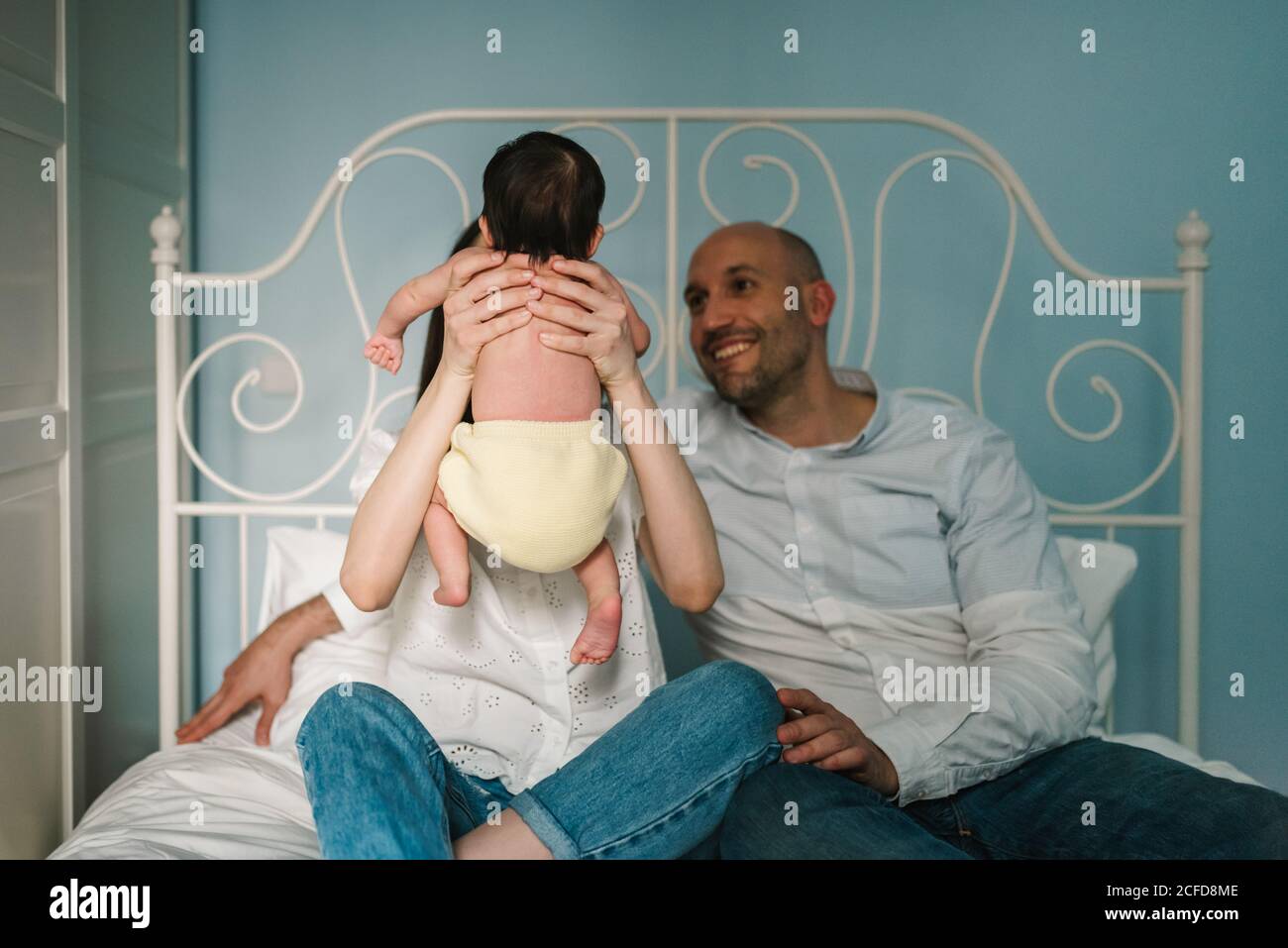 Parents hugging baby on bed Stock Photo - Alamy