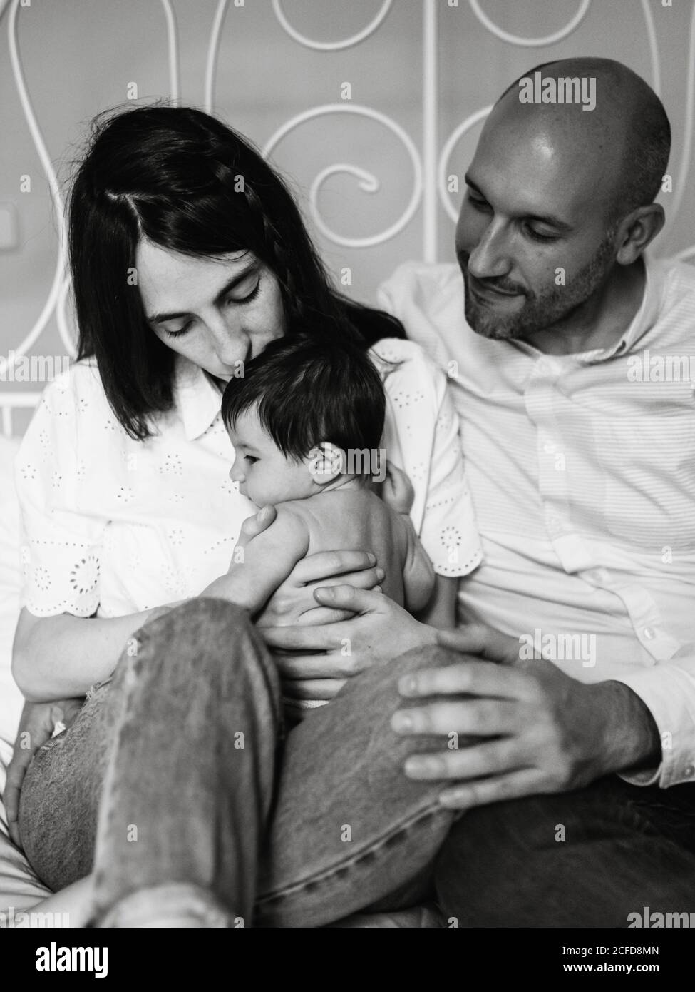 Parents hugging baby on bed Stock Photo - Alamy
