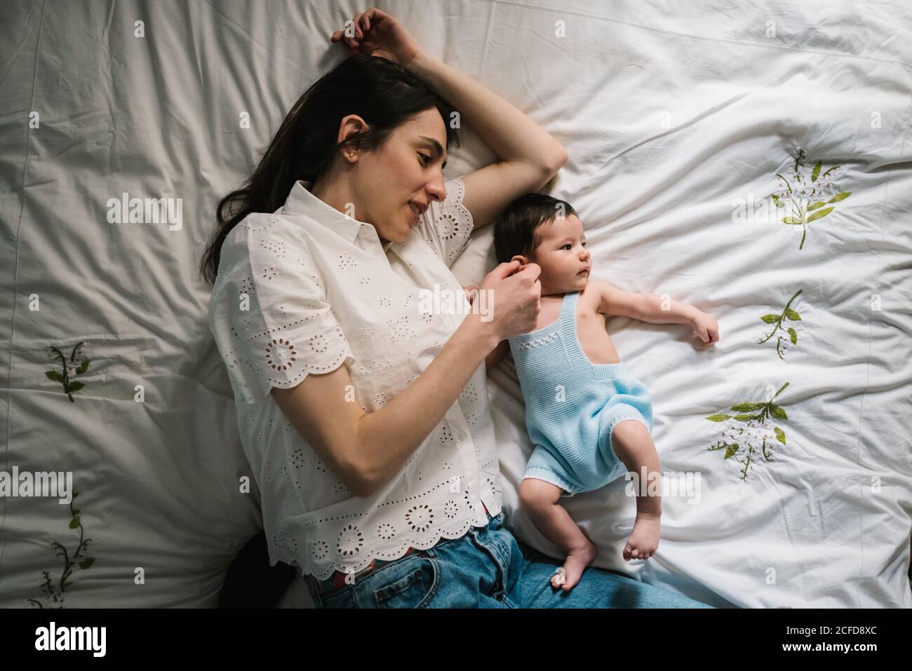 Beautiful adult Woman gently touching sweet baby while lying on ...