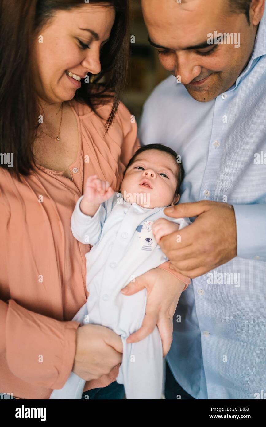 Happy parents while holding and hugging crying baby at home Stock Photo ...