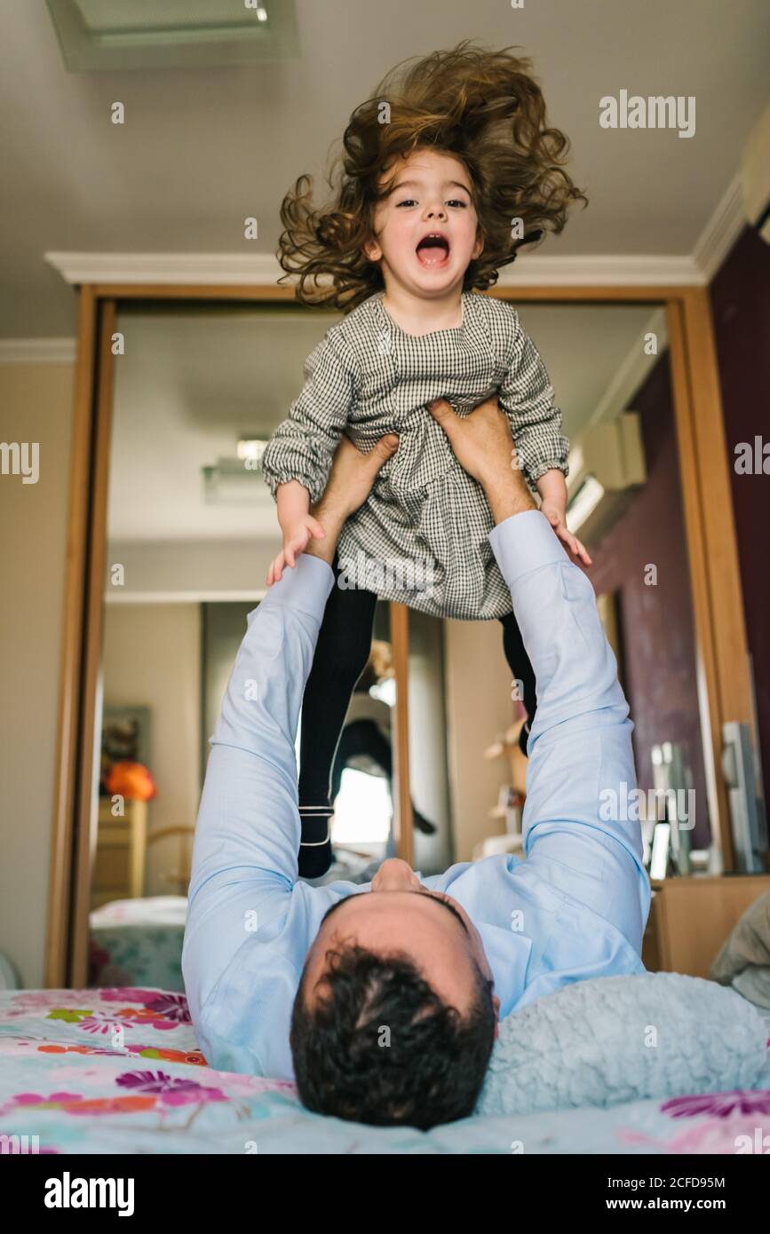 faceless dad having fun with happy daughter holding on hands while ...