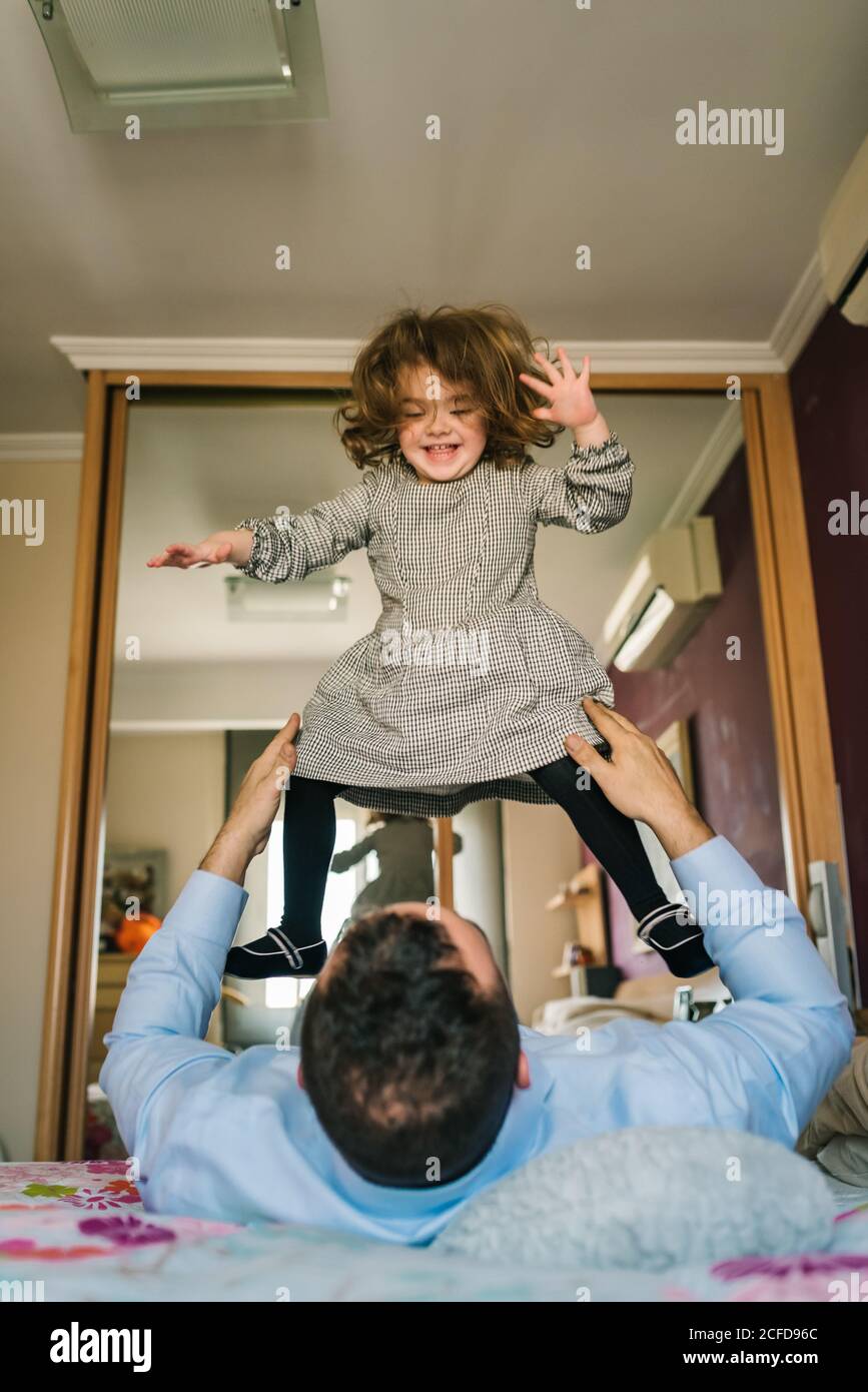 faceless dad having fun with happy daughter holding on hands while ...