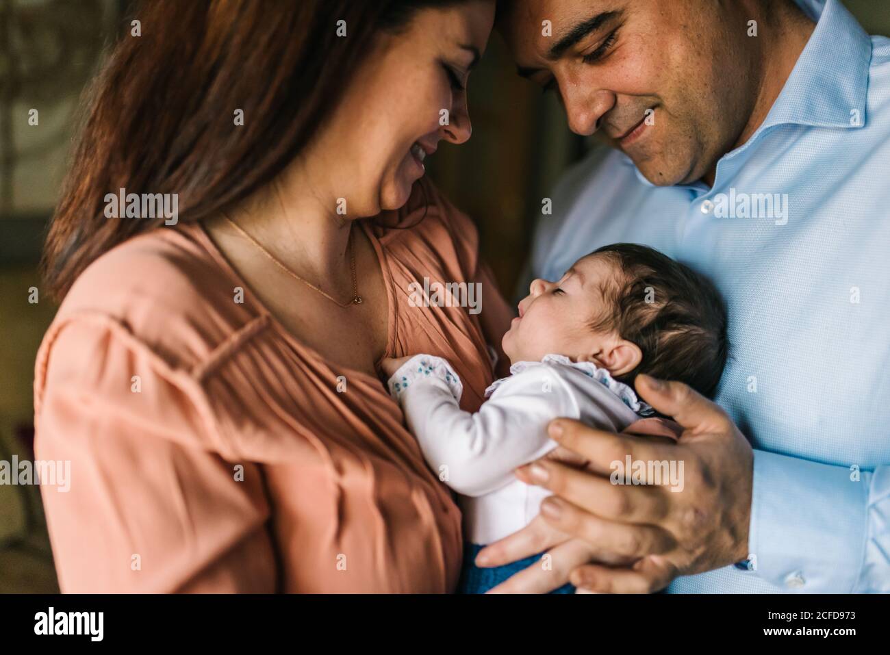 Happy parents while holding and hugging crying baby at home Stock Photo ...