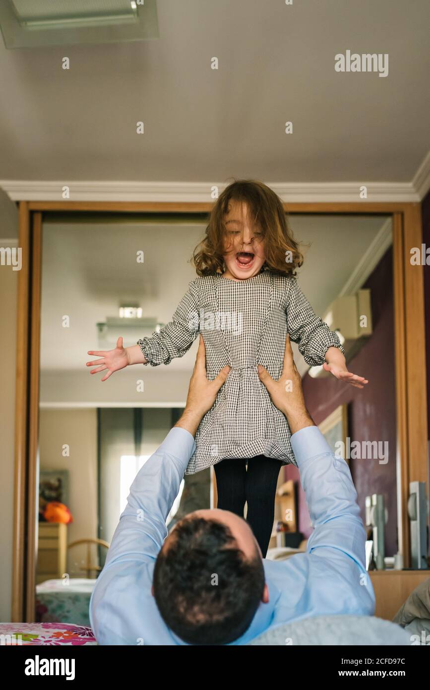 faceless dad having fun with happy daughter holding on hands while ...